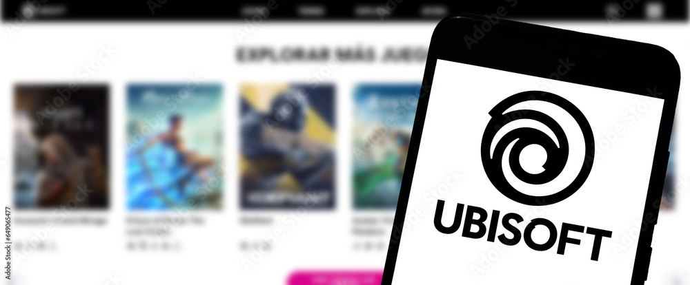 Logo of Ubisoft on smartphone screen with defocused Ubisoft website ...