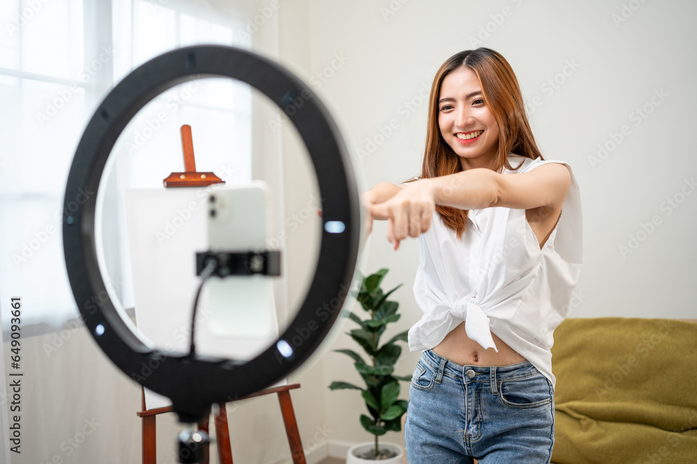 Young trendy influencer asian woman dancing on mobile phone at home in ...