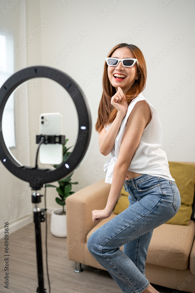 Young trendy influencer asian woman dancing on mobile phone at home in ...