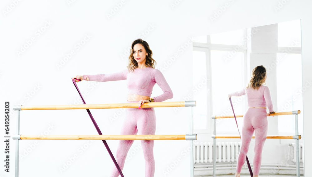 Slim ballerina woman girl in pink tracksuit. Stretching at ballet ...