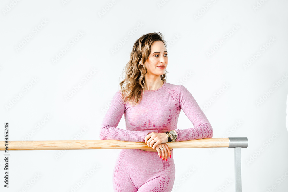 Slim ballerina woman girl in pink tracksuit. Stretching at ballet ...