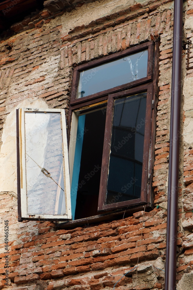 Old abandoned house facade with decaying brick wall and window hanging ...