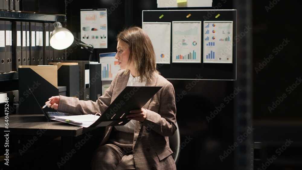 Female private detective enters office space reviewing evidence and ...