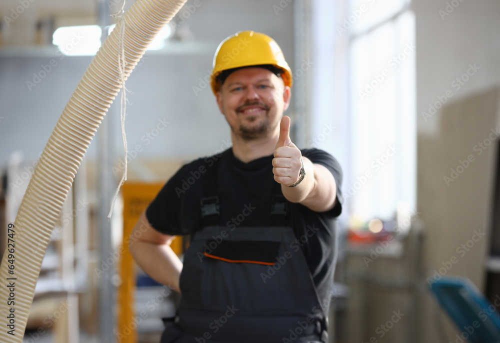 Smiling worker in yellow helmet show confirm sign with thumb up at arm ...