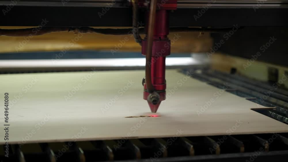 A close-up of a laser wood cutting machine cuts a particle board, and ...