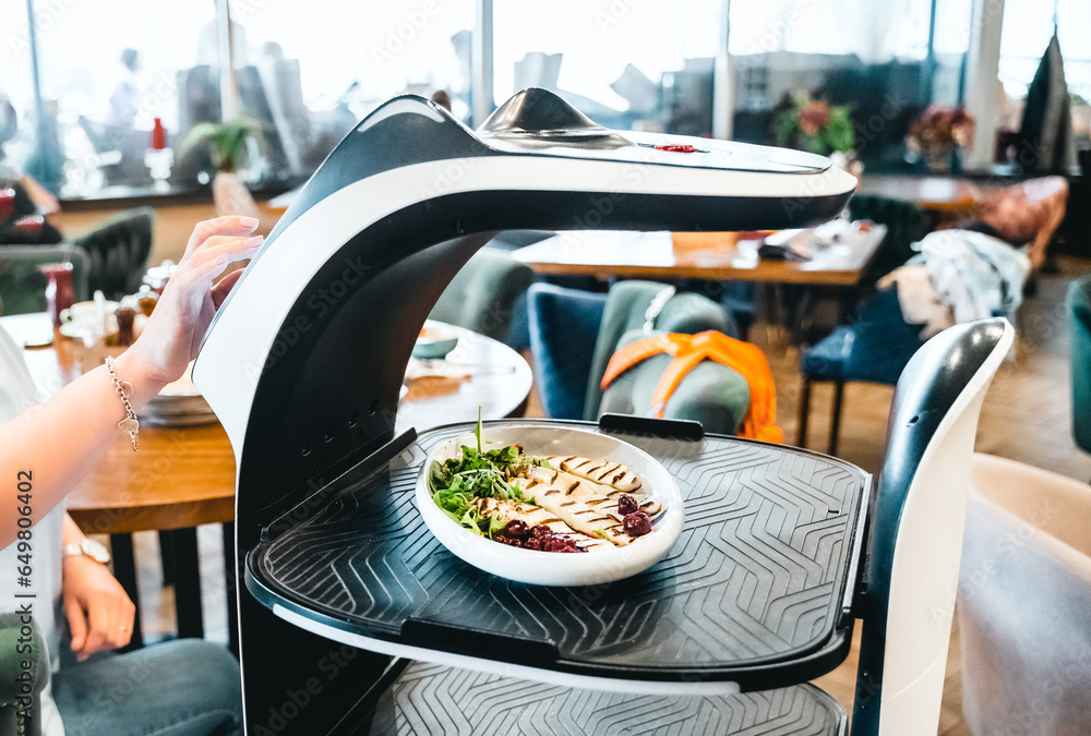 Robot waiter serve food at modern restaurant table.Offering innovation ...