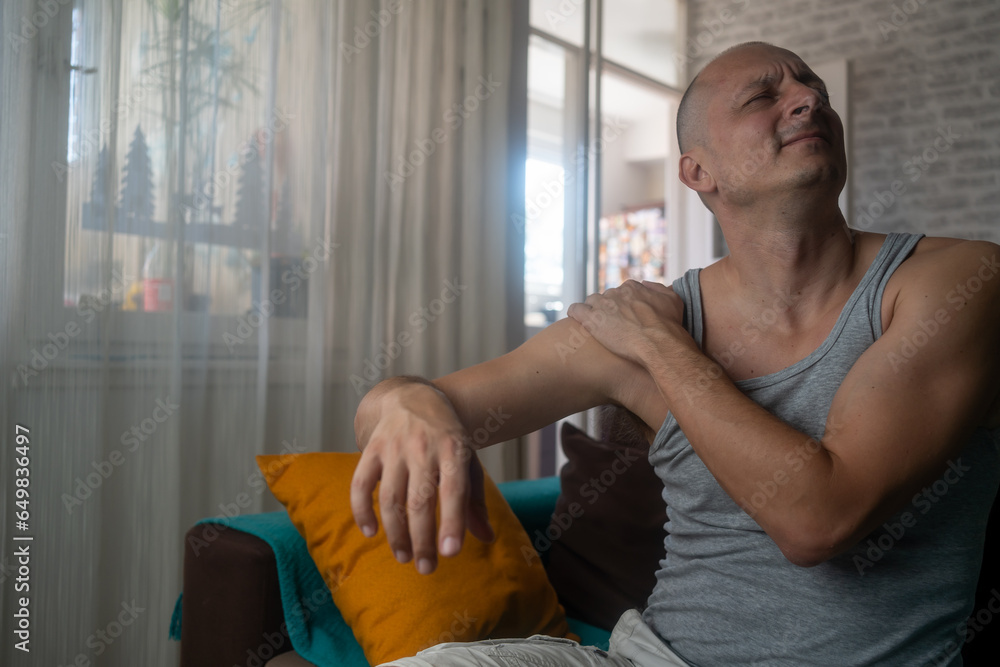 man touching his shoulder, suffering from shoulder pain, sciatica ...
