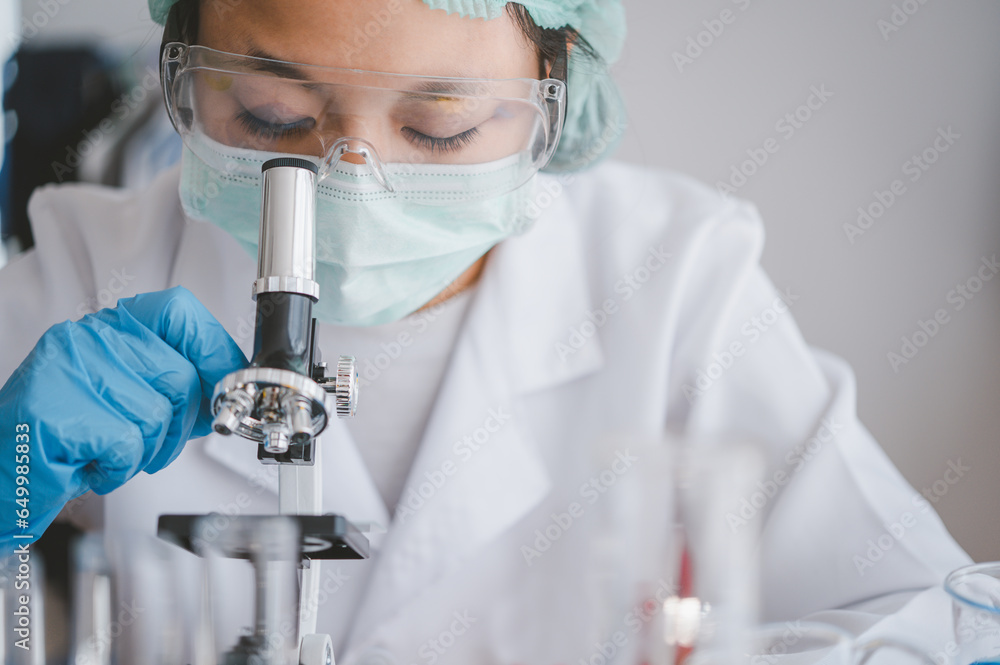 female medical researcher looking at a microscope in a medical ...