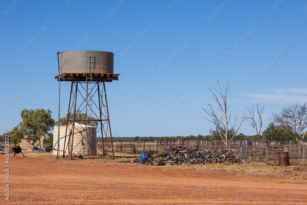 Water tanks and a wood pile in a farm yard in outback country in ...