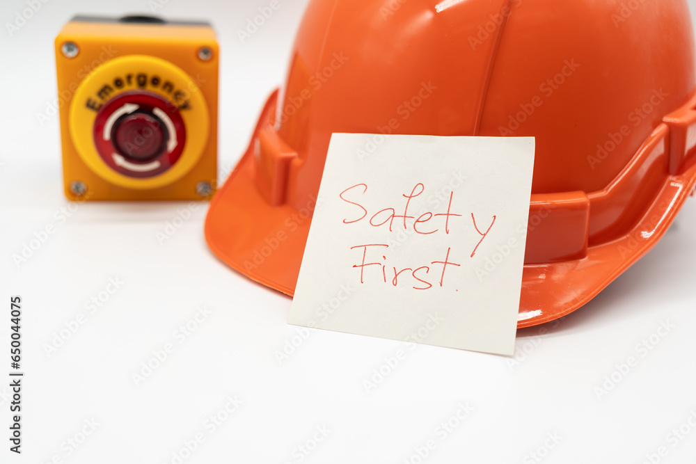 Orange safety hat with message Safety First and Emergency Stop Button ...