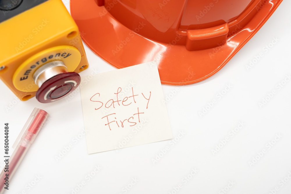Orange safety hat with message Safety First, Red Pen and Emergency Stop ...