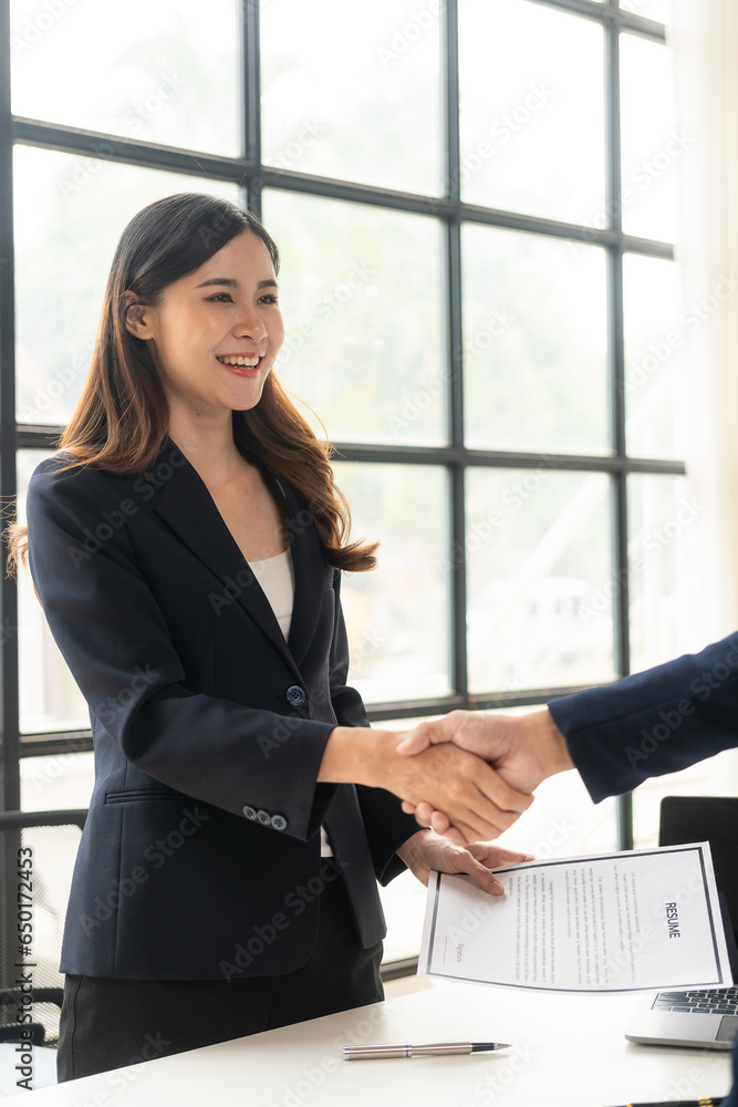 Close-up of a businessman shaking hands with a young Asian female job ...