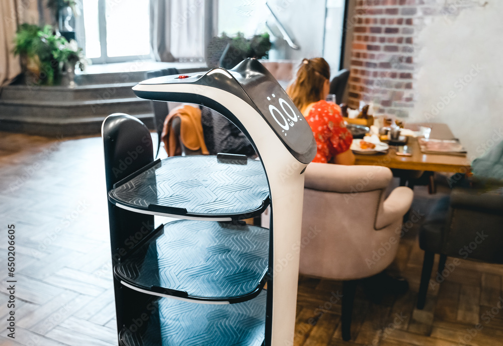 Robot waiter serve food at modern restaurant table.Offering innovation ...