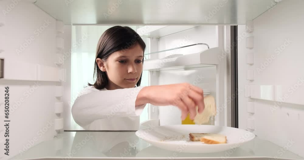 A disheartened schoolboy opens the refrigerator and inspects a piece of ...