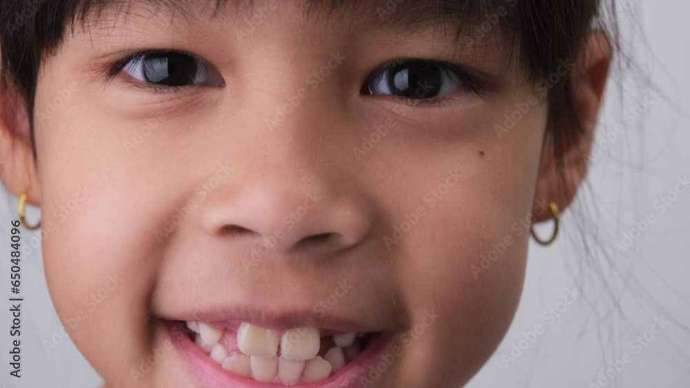 Close-up of cute young girl smiling wide, showing empty space with ...