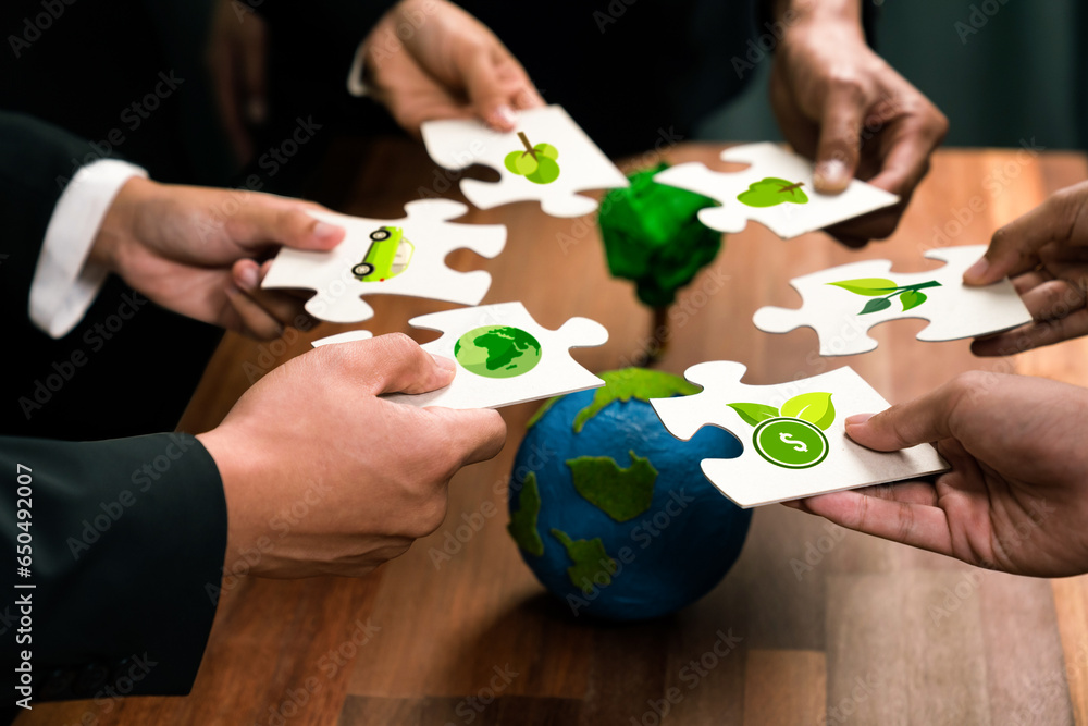 Cohesive group of business people holding eco icon jigsaw puzzle pieces ...
