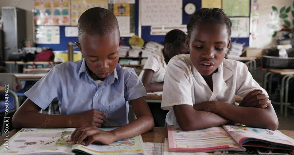 Close-up. Black African school children sitting at desk reading at a ...