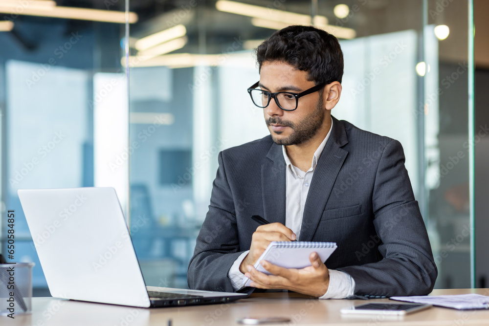 Serious and concentrated thinking businessman watching webinar online ...