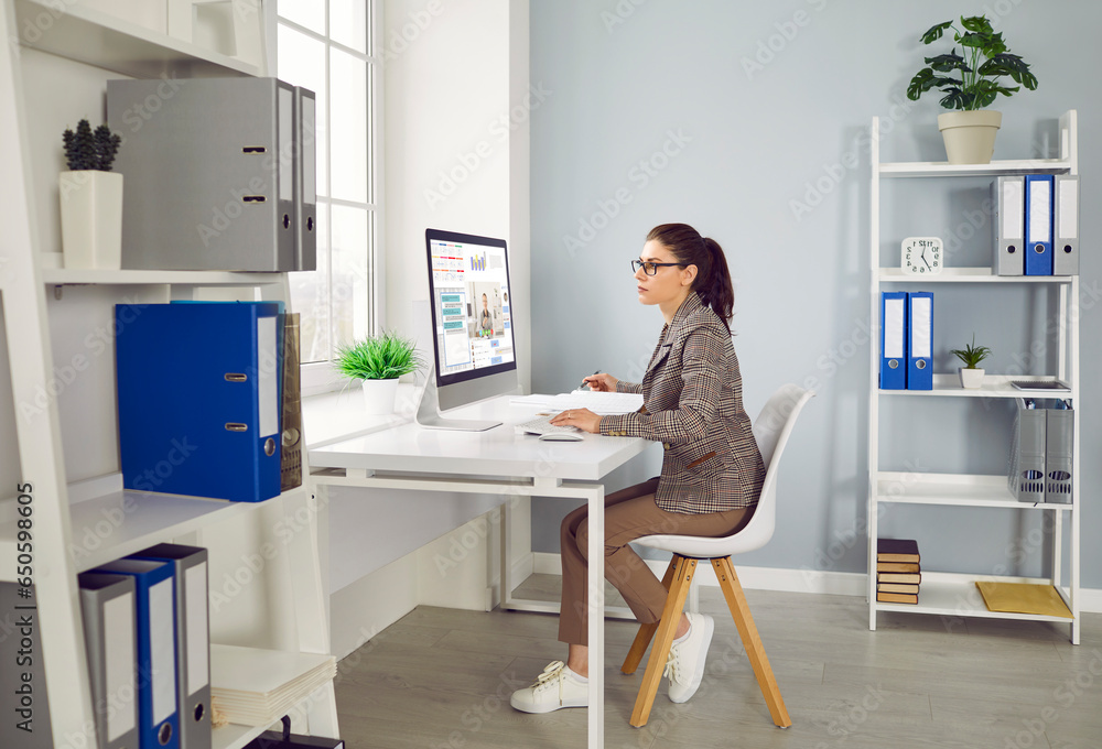 Female office worker sitting in front of her computer. Young woman in a ...