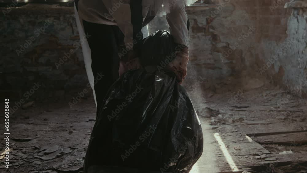 Tilt up shot of psychopath in clown costume dragging dead body in ...