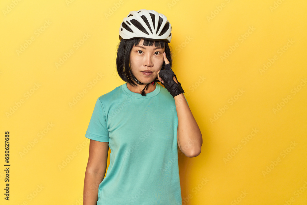 Cyclist outfit and gear, yellow background pointing temple with finger ...