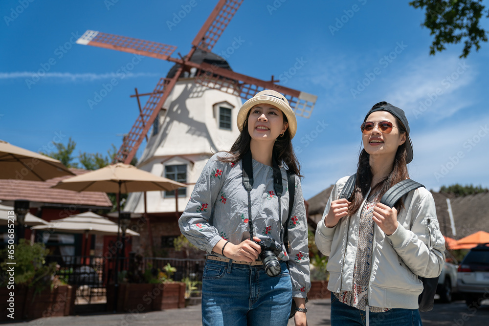 two happy asian chinese girl travelers carrying camera and looking into ...