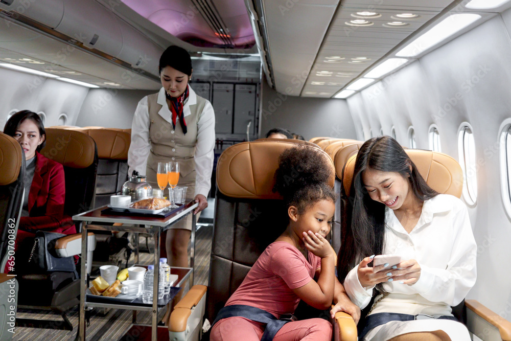 Happy African girl kid and woman passenger look at mobile phone during ...