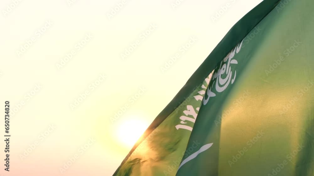 Saudi Arabia’s 93rd National Day. Saudi Arabia flag waving in sky against wind, beautiful sunset ...