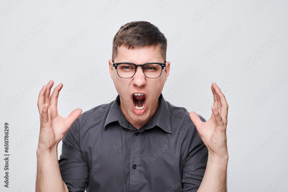 Portrait of angry young man screaming holding hands in furious gesture ...