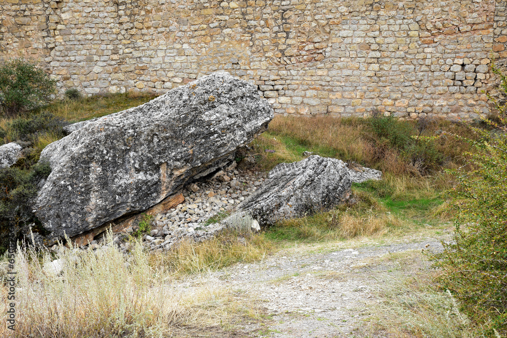 Rocas de gran tamaño al lado de una pared de ladrillo, en las montañas ...