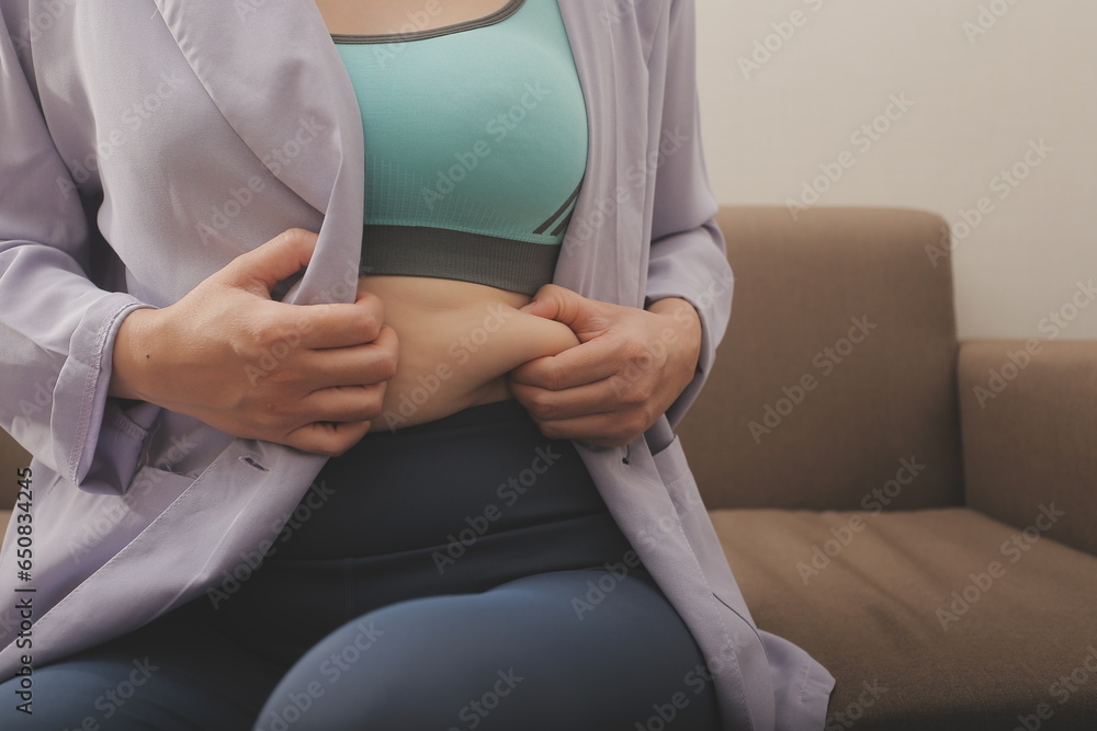 A woman shows an inflated thick belly, the concept of excess weight and ...