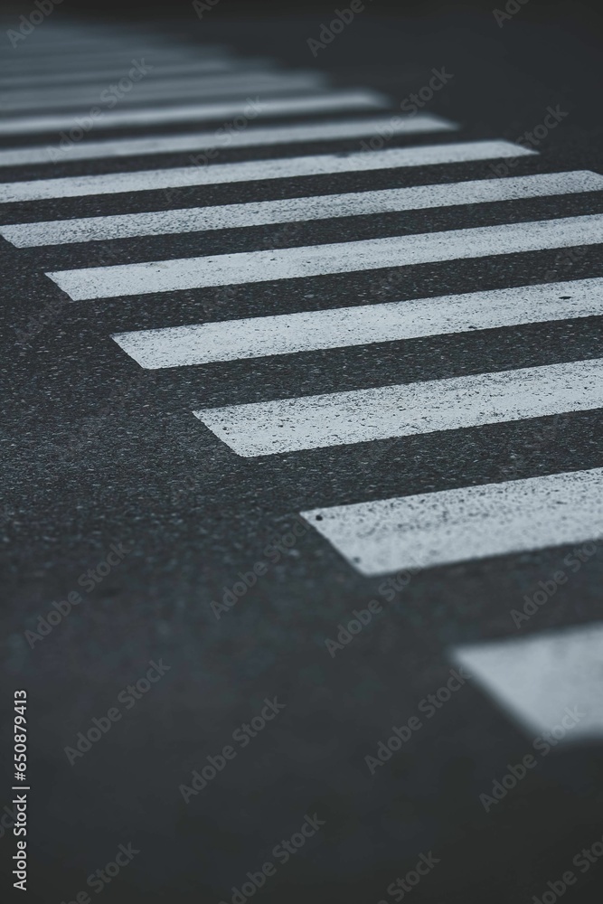 Asphalt road marked with white lines to signify a designated crosswalk ...