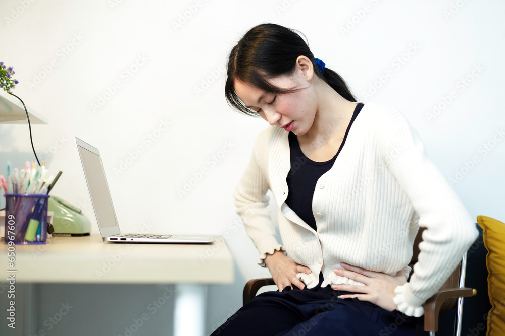 Working woman with laptop at table hand touching abdomen having stomach ...