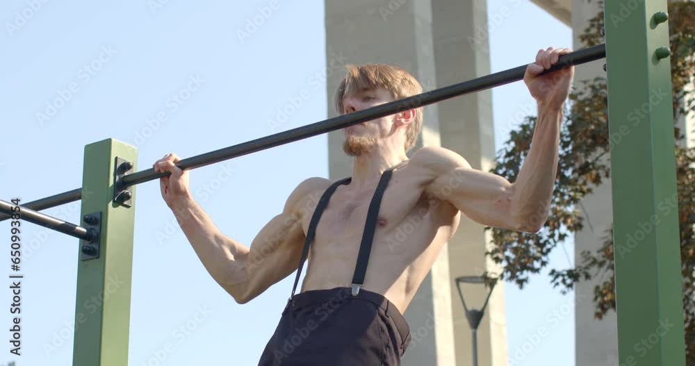 Man demonstrates masculinity while exercising outdoors. Pull-ups with ...