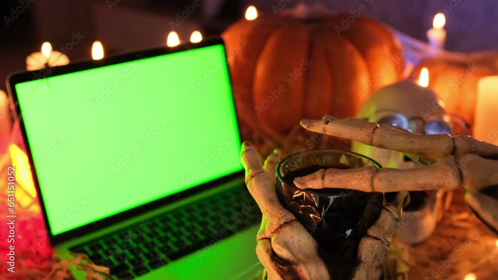Creepy monster fingers stroke glass of blood near laptop with green ...