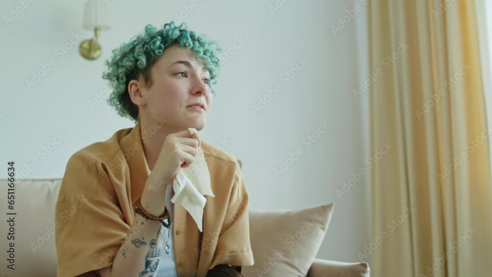 Tilt up shot of crying gen Z girl with prosthetic arm sitting on sofa ...