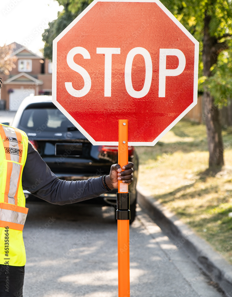 Security guard conducting traffic control with stop slow sign according ...