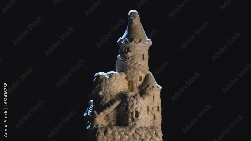 Sand castle with windows rotating with black background backlit with ...