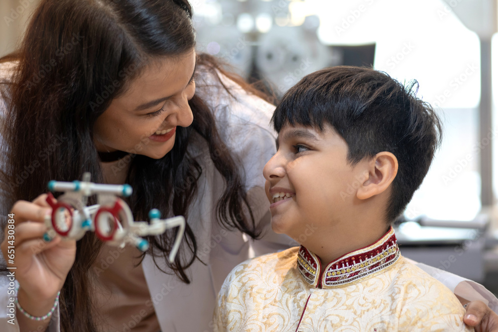 Indian female optometrist shows trial frame to boy, experimental frame ...