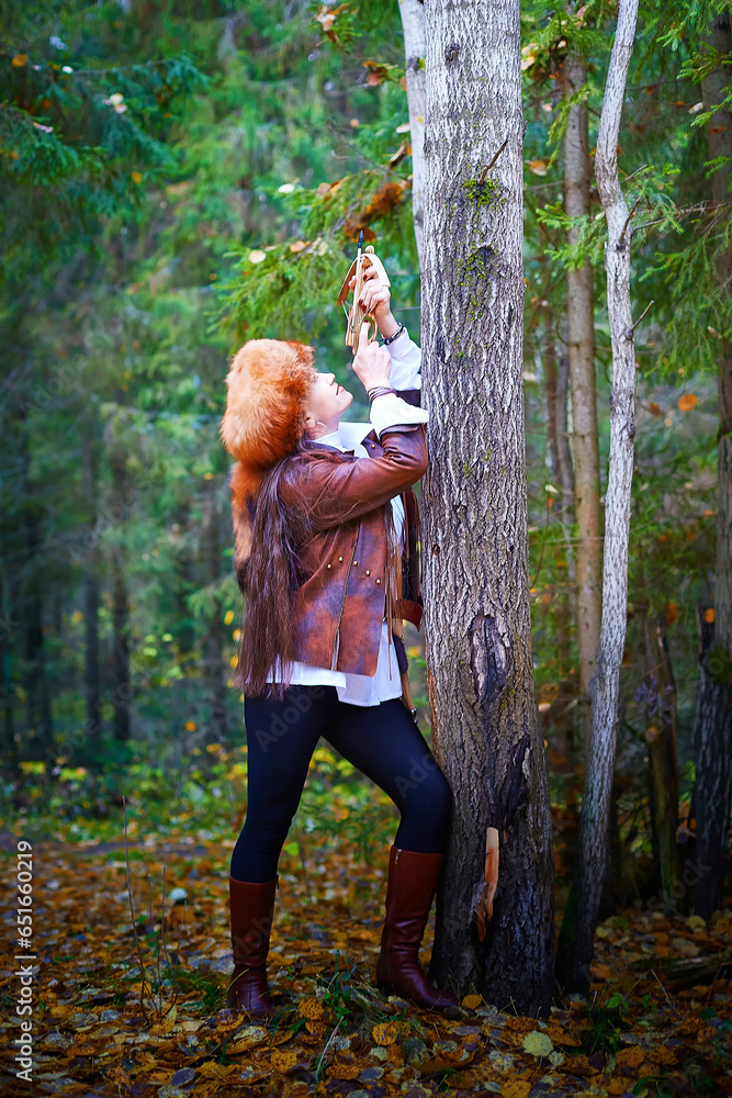 Girl in a leather jacket, a big red fox fur hat and with a crossbow in ...