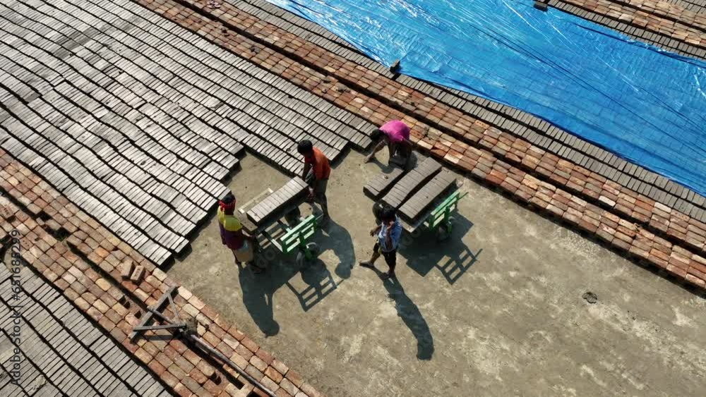 Workers in a brickfield or brick factory, making bricks from mud. The ...