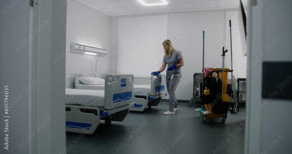 Adult nurse mops floor between beds in hospital ward. Health worker ...