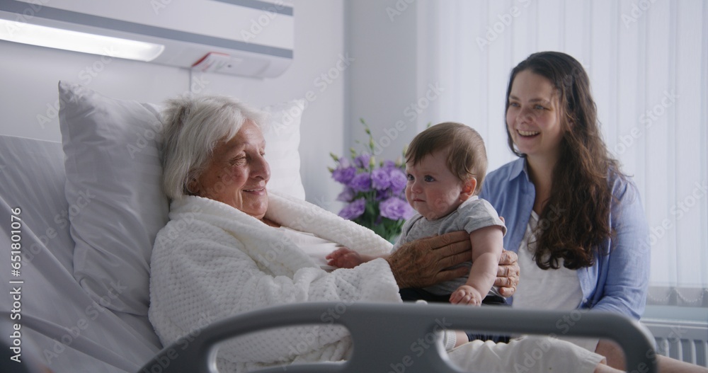 Female elderly patient lies in bed in bright hospital ward, plays with ...