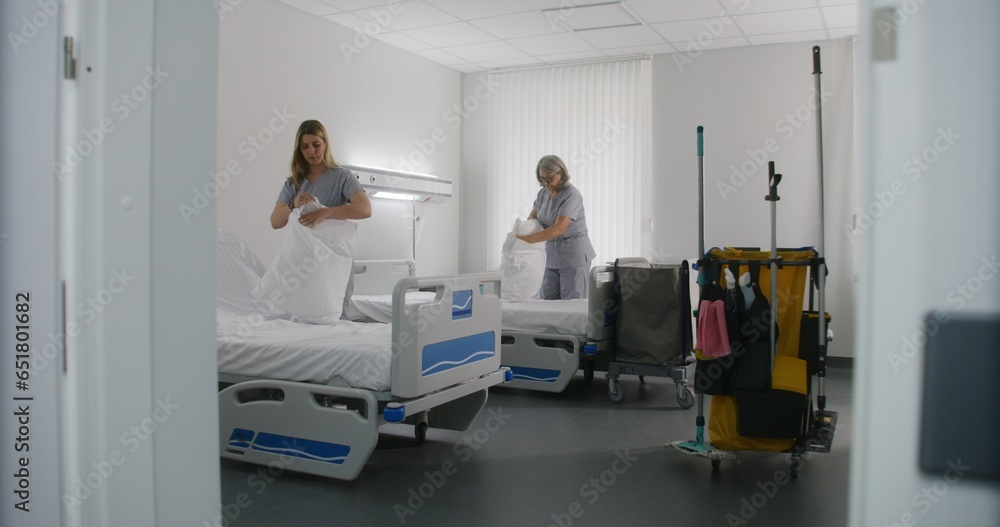 Adult cleaner mops floor with broom in hospital room. Mature health ...