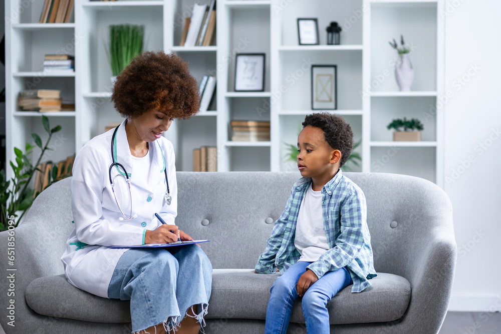 Young african american female doctor pediatrician talking to kid boy ...