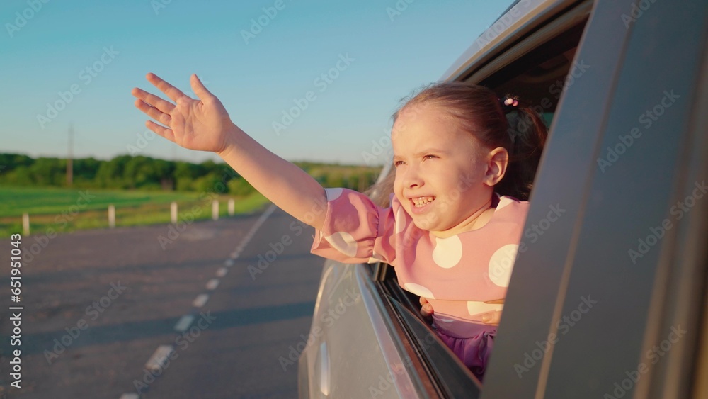 Child, stretching his hand out of car window, laughs. Girl child looks ...