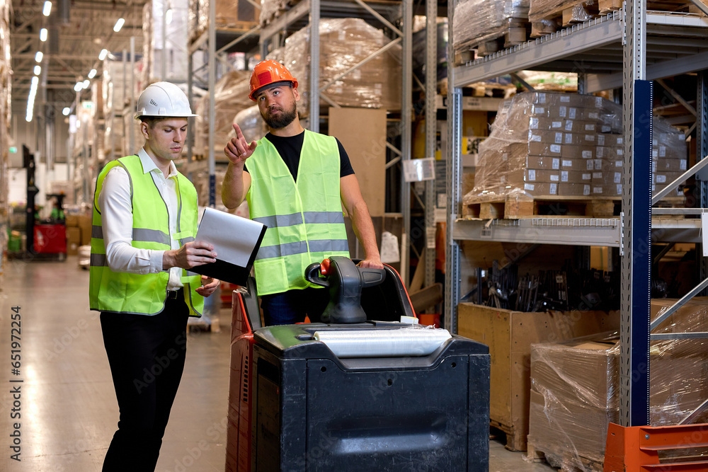 warehouse workers men in reflective jackets pulling a pallet truck and ...