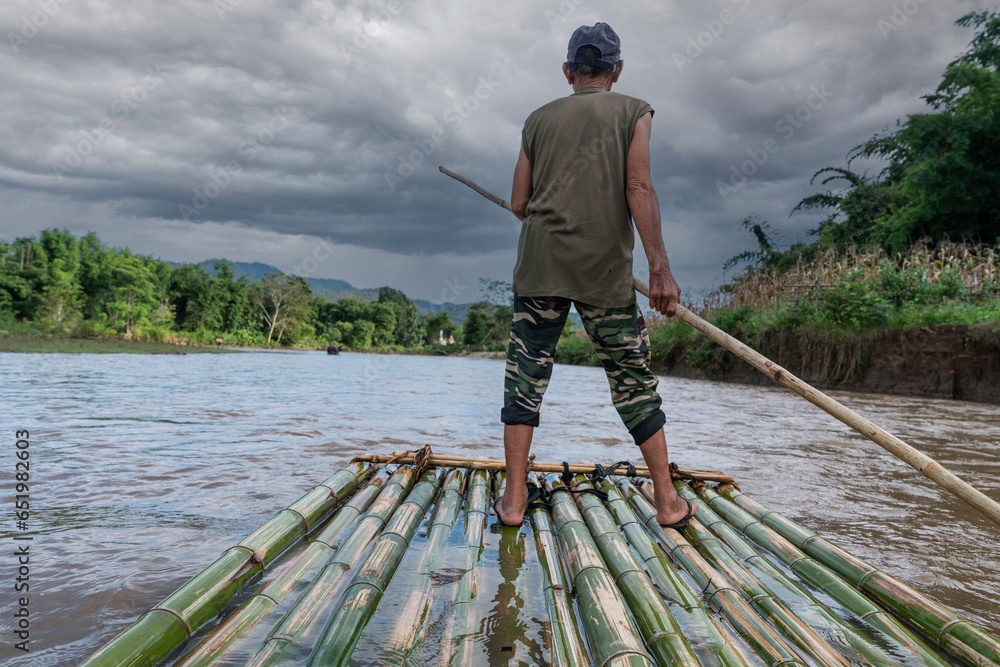man villagers carry bamboo sticks to guide the bamboo raft down the ...