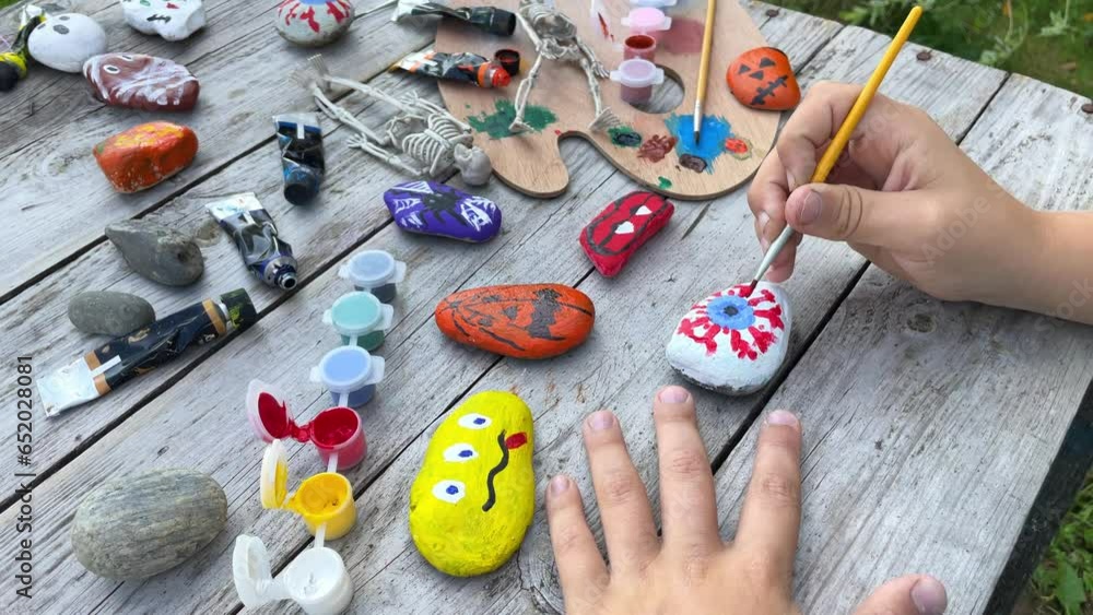 Diy concept. A detailed picture of a child's hands drawing on stones ...