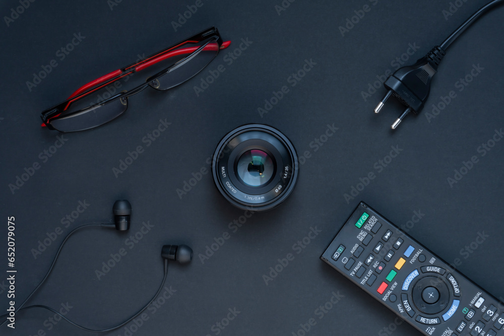 Camera lens on a black background with glasses and a TV remote ...